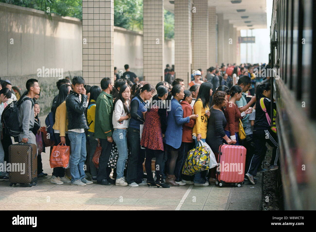 --FILE--A crowd of pasengers queue up to board a "green-skin" train at ...