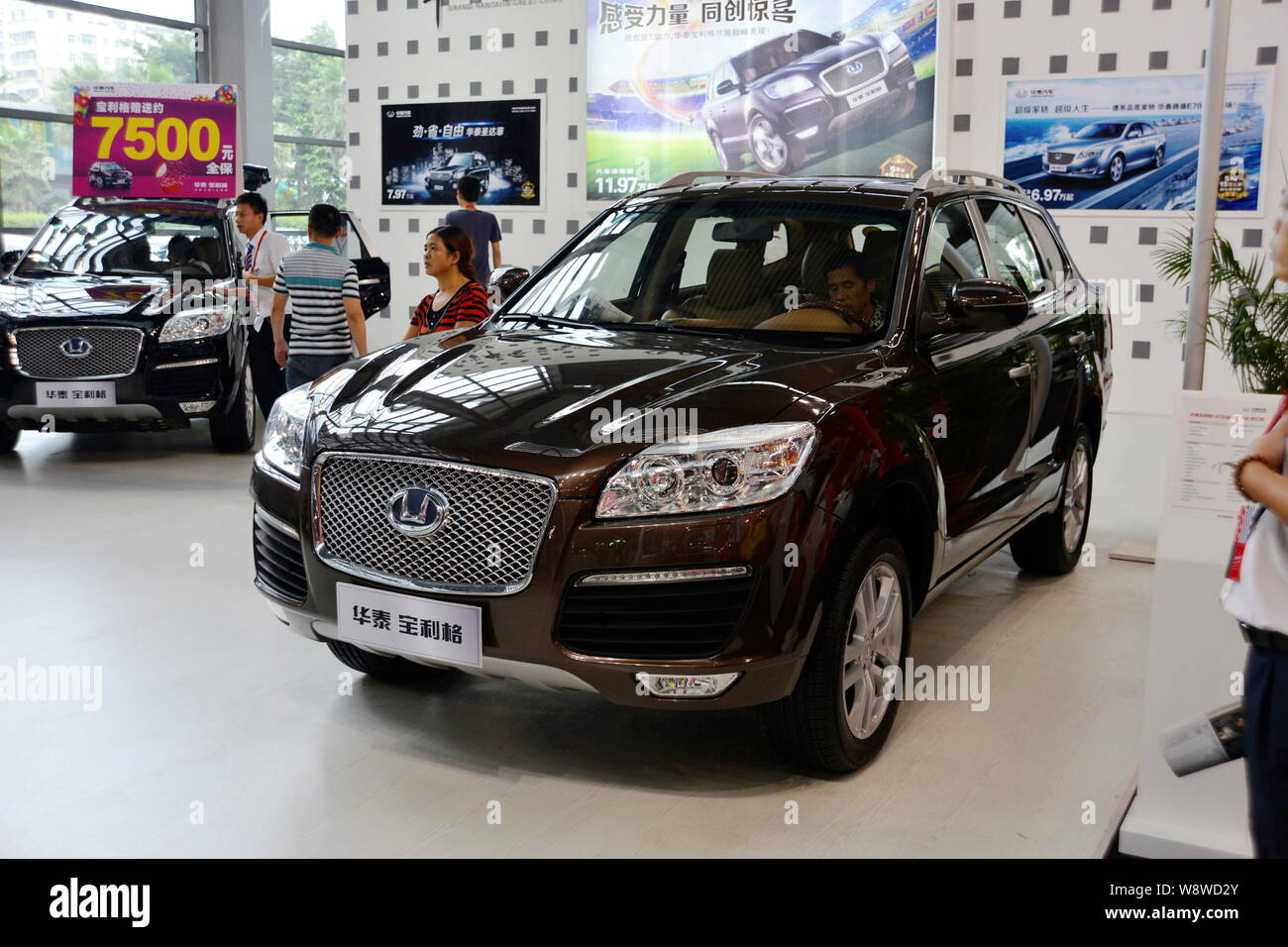 --FILE--Visitors look at or try out Bolgheri cars of Hawtai Motor at an ...