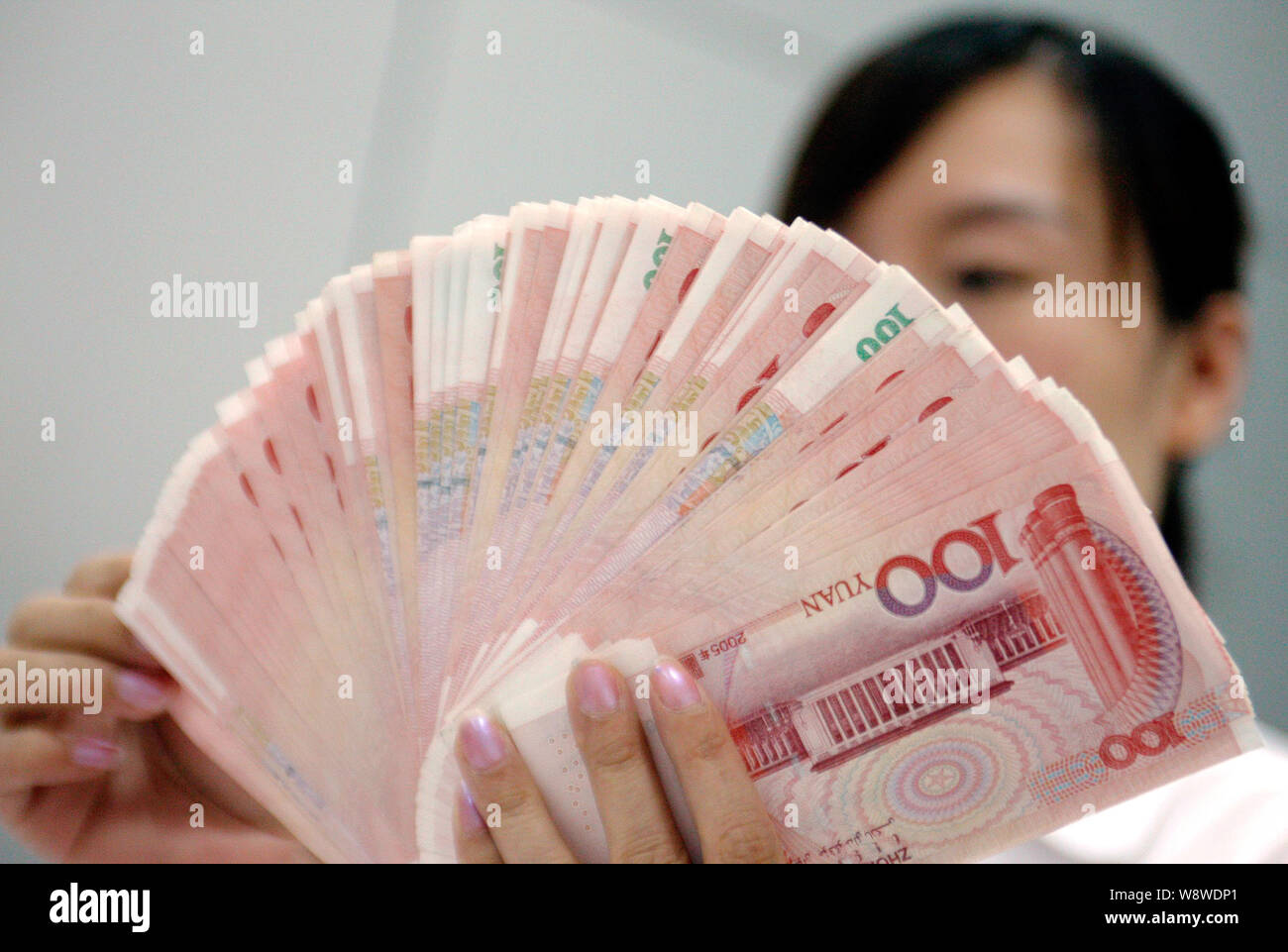 --FILE--A Chinese employee counts RMB (renminbi) yuan banknotes at a ...