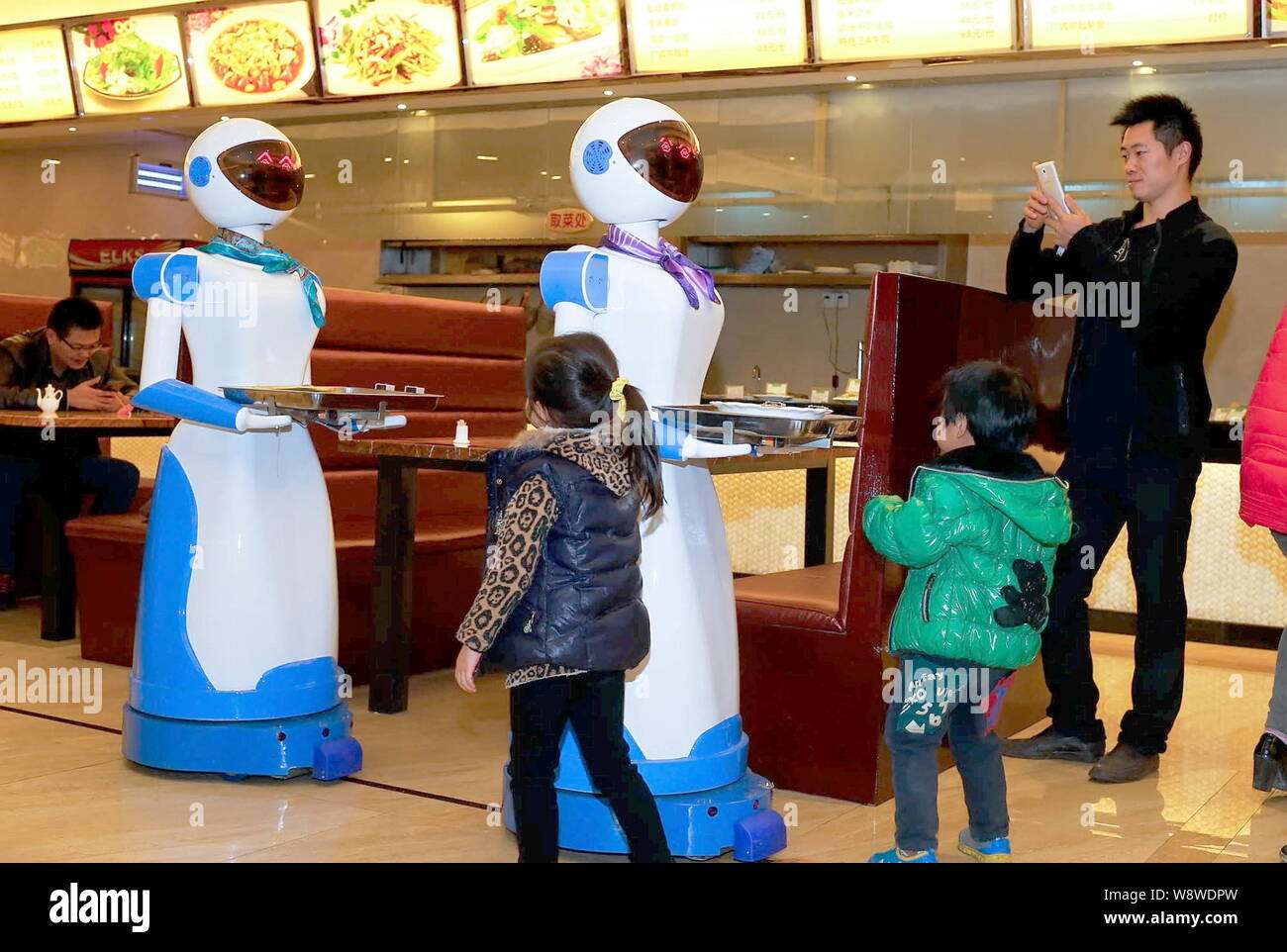 Customers look at robot waiters at a restaurant in Cixi city, east ...