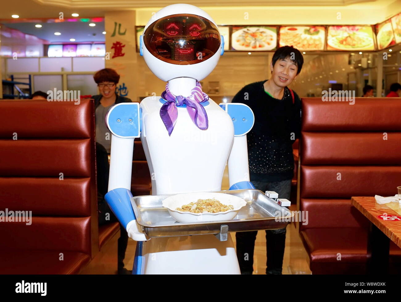 Customers look at a robot waiter at a restaurant in Cixi city, east ...