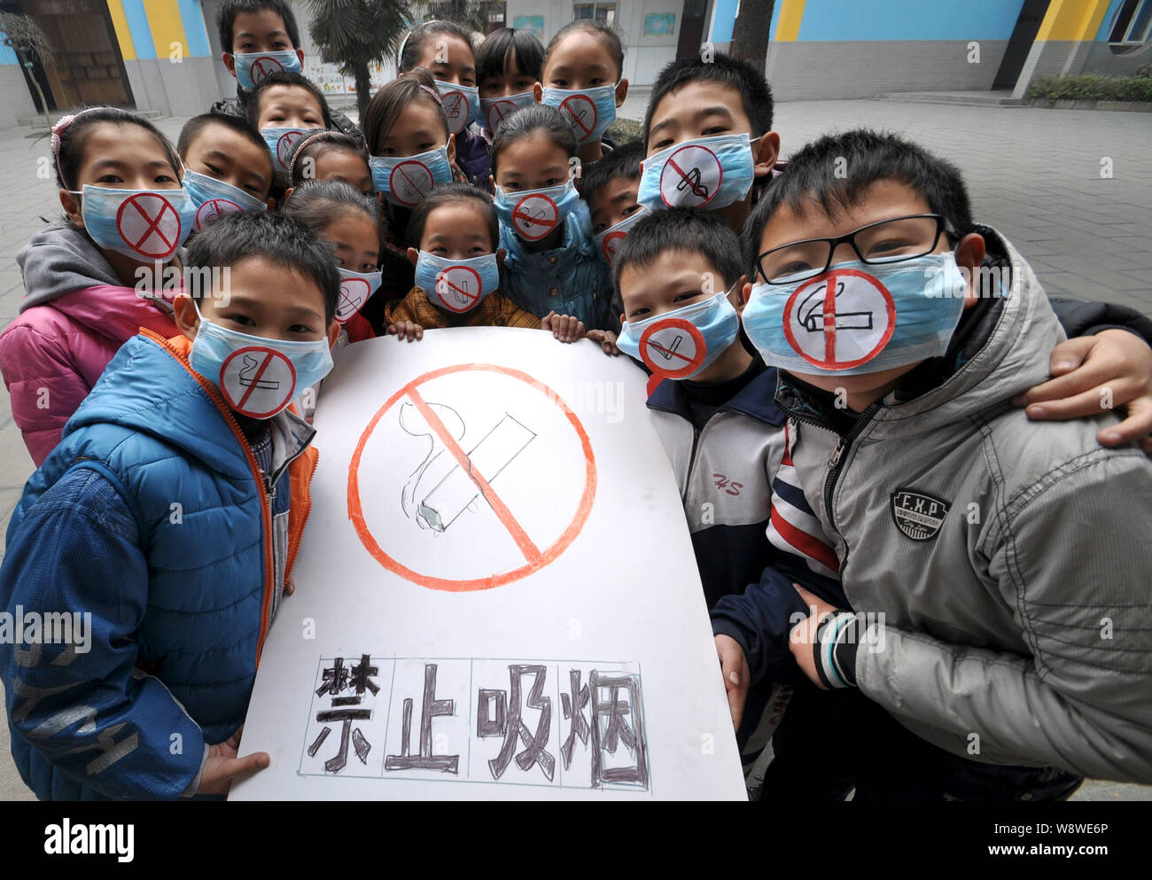 --FILE--Young Chinese students wearing face masks with No-Smoking signs ...