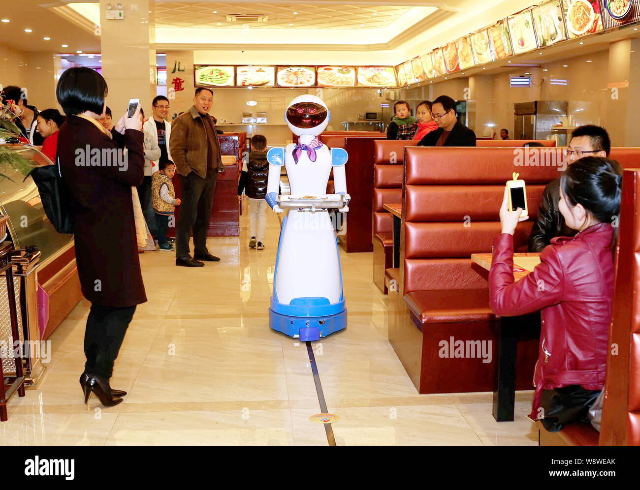 Customers take photos of a robot waiter at a restaurant in Cixi city ...