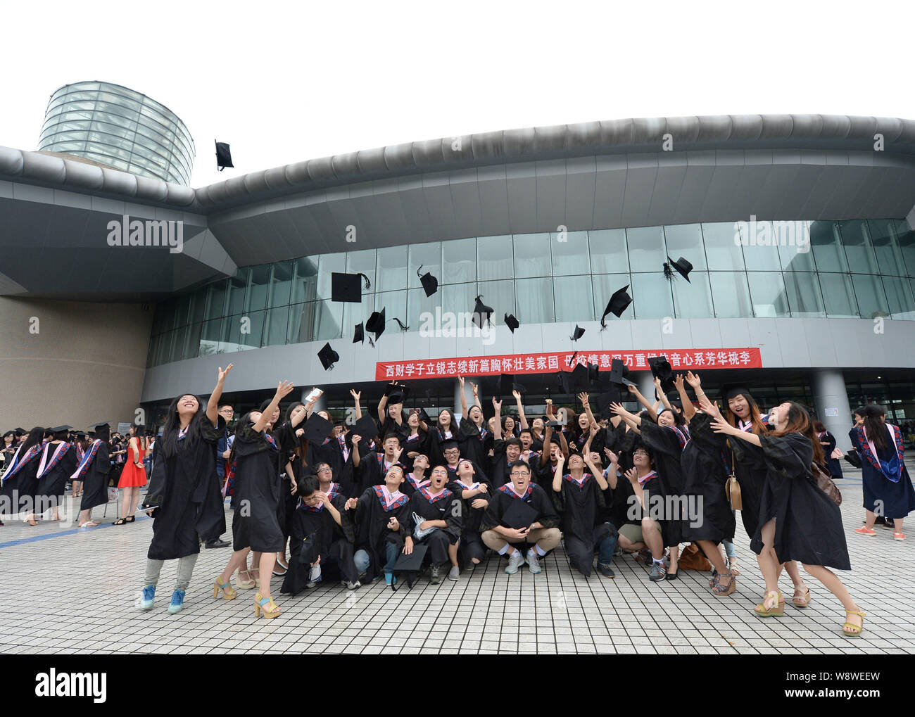 --FILE--Chinese graduates dressed in academic gowns throw hats into the ...