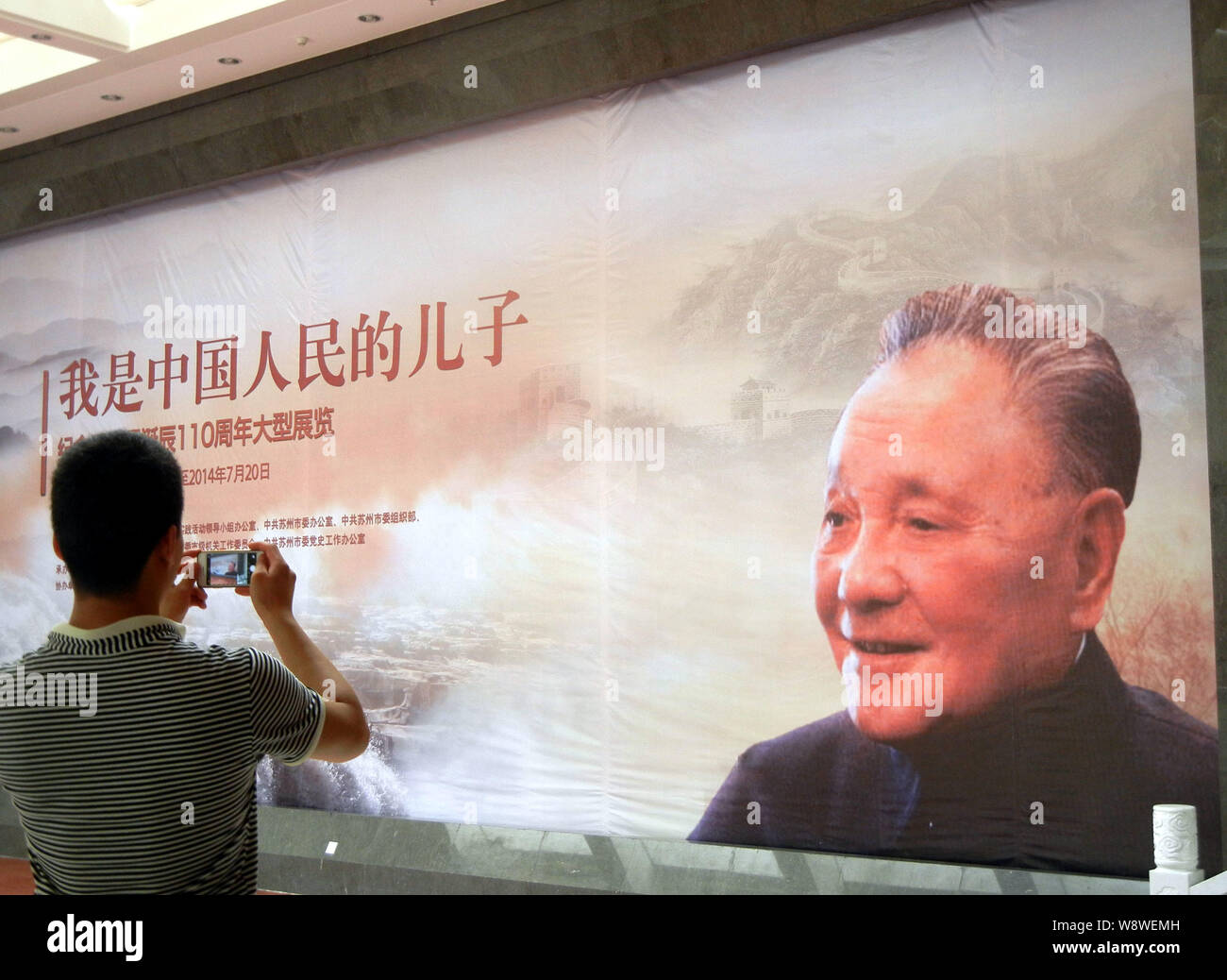 --FILE--A visitor takes photos of a poster with an image of the late ...