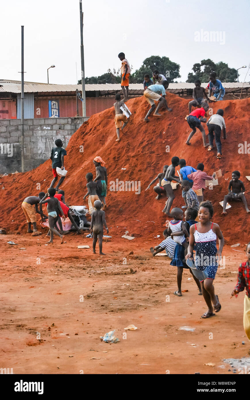 Children playing on a red sand hill on the street of Angola capital ...
