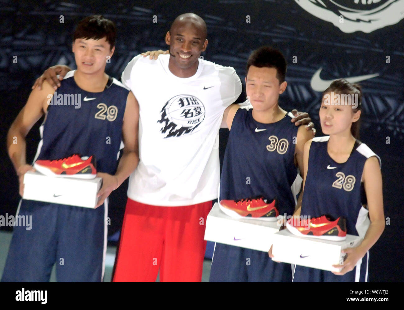 NBA star Kobe Bryant, second left, poses with fans during a basketball ...
