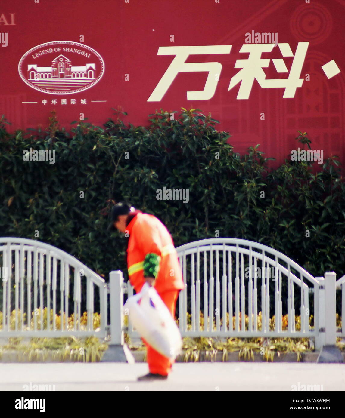 --FILE--A Chinese cleaner clears away garbage in front of an ...