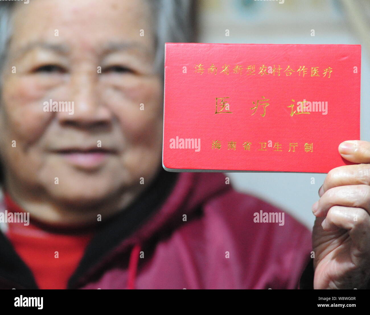 An elderly local Chinese resident shows her health insurance card in ...