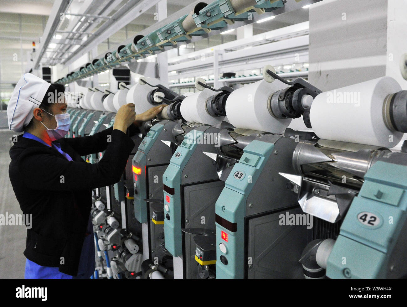 --FILE--A female Chinese worker handles production of yarn at a textile ...