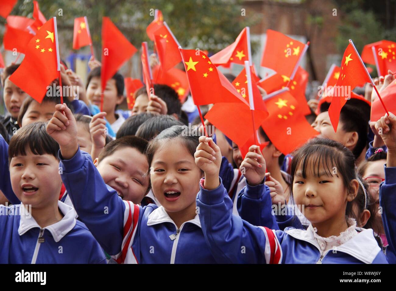 Young Chinese students wave small Chinese national flags to celebrate ...