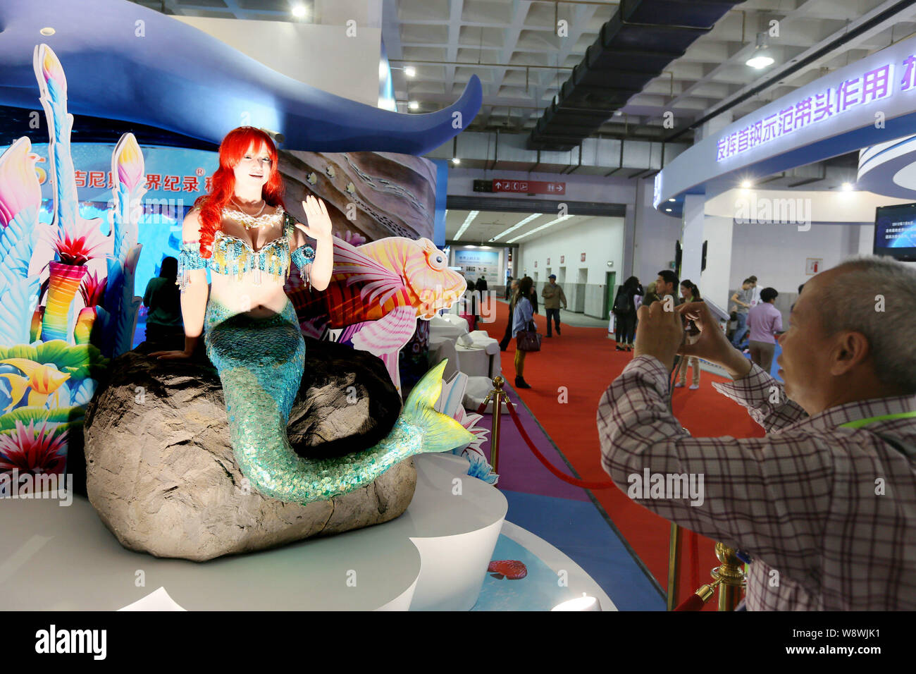 A visitor takes photos of a mermaid robot on display during the 17th ...