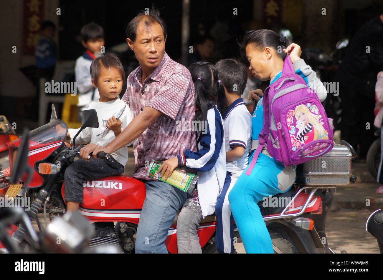 --FILE--Two adults and three young kids ride a motorcycle as they leave ...
