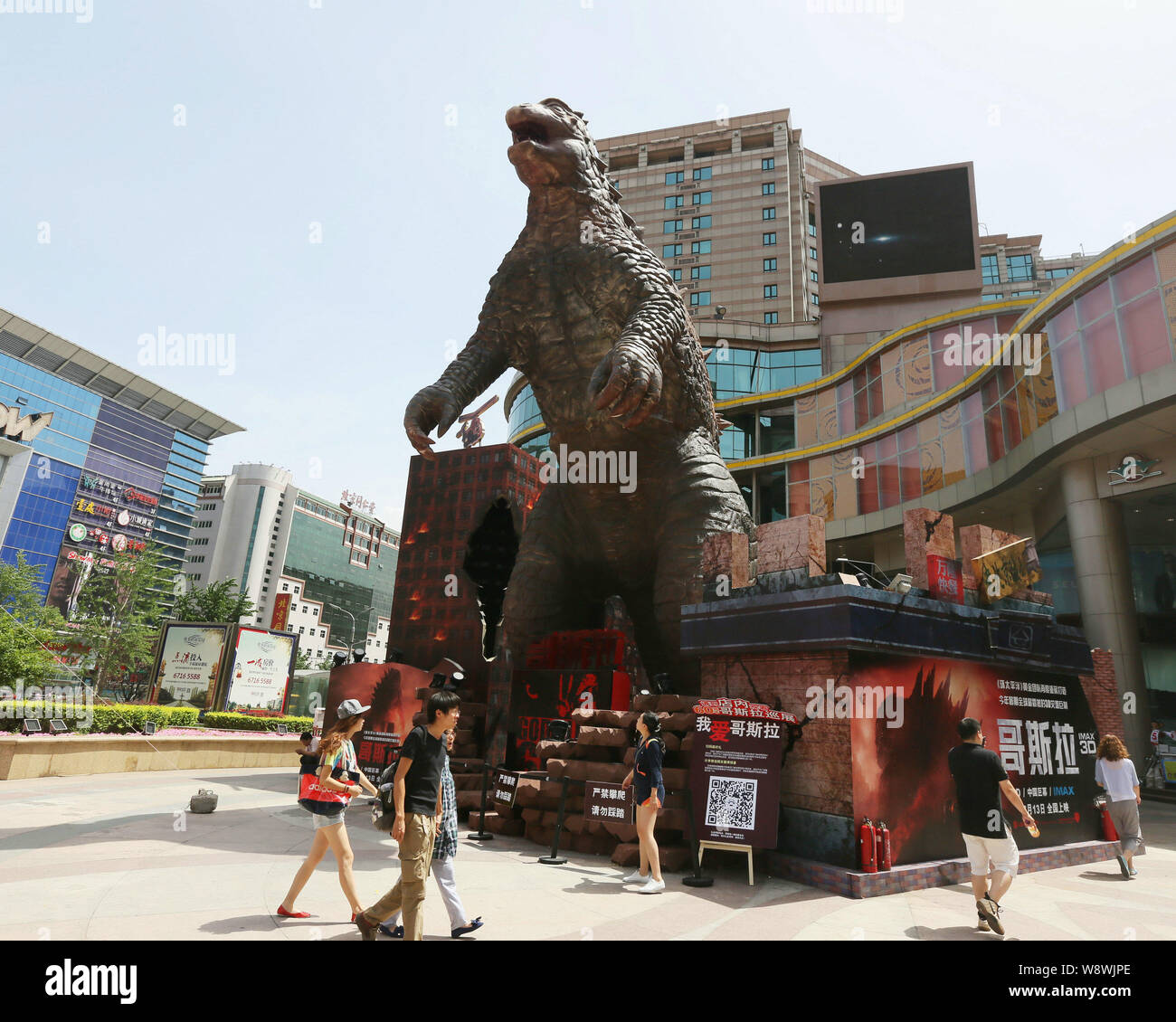 --FILE--Pedestrians walk past a giant model of Godzilla in front of a ...
