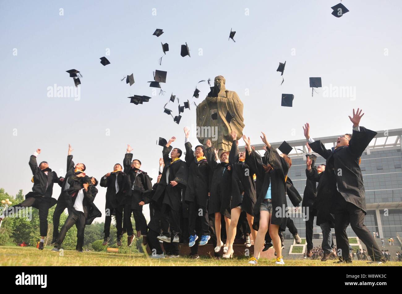 --FILE--Chinese graduates dressed in academic gowns throw hats into the ...