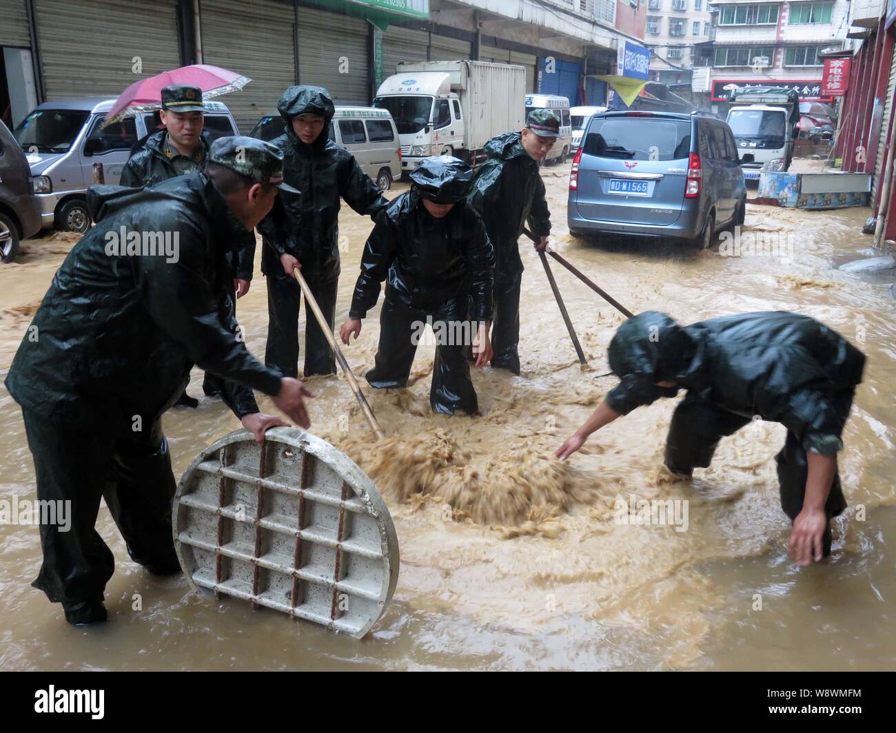 Chinese rescuers clear away mud on a flooded street caused by ...