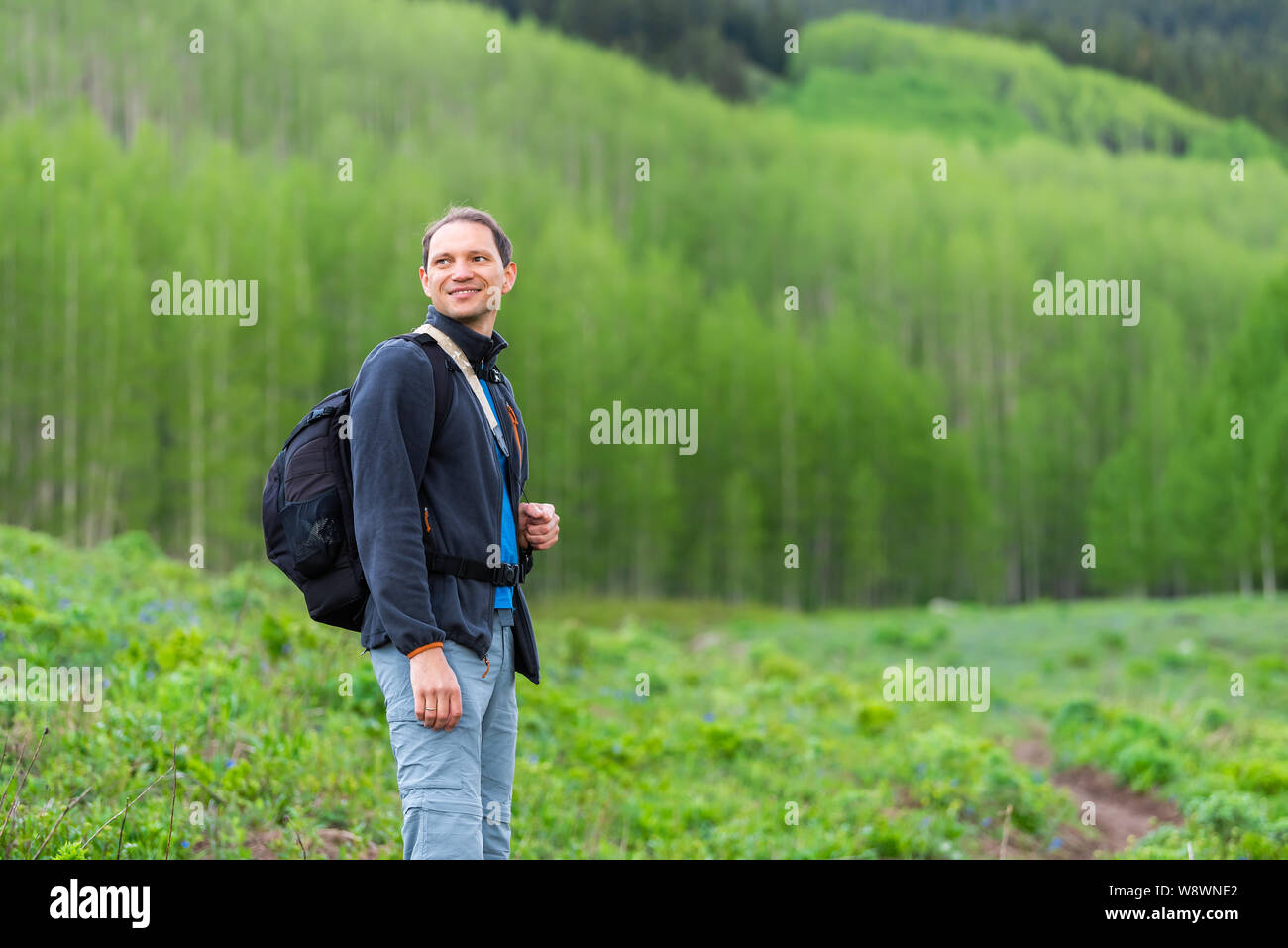 Man standing smiling looking back with backpack on Snodgrass trail with ...