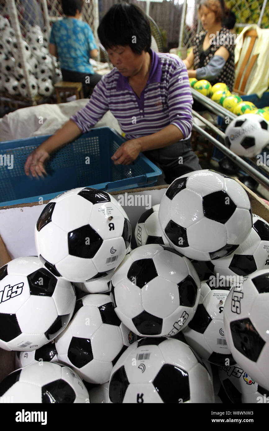 Chinese workers examine newly-made footballs at a sports goods factory ...