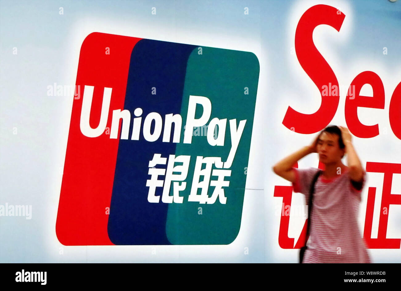 --FILE--A pedestrian walks past an advertisement for UnionPay in ...