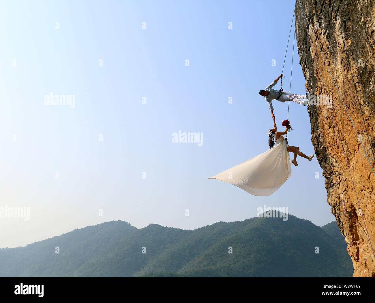 Mr.Zheng, a rock climber, and his bride climb up a 20-meter-high cliff ...