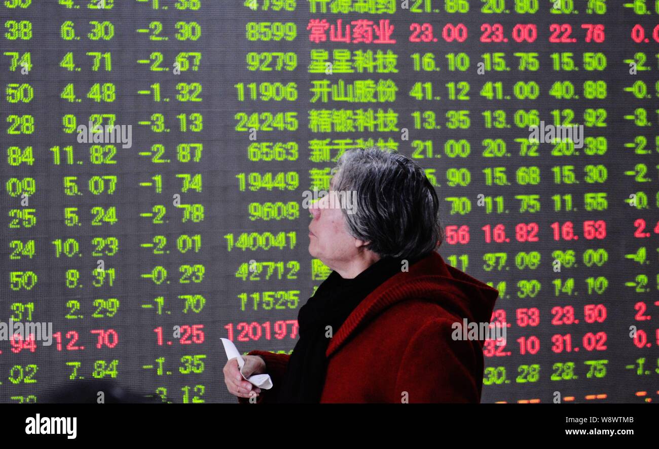 A Chinese investor looks at prices of shares (red for price rising and ...