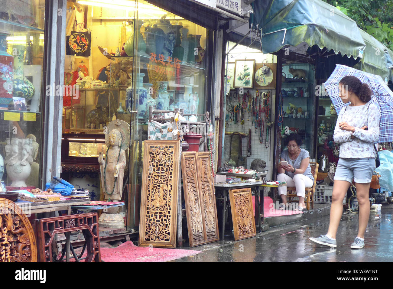 A foreign tourist walks past shops at the Shanghai Dongtai Road Antique ...