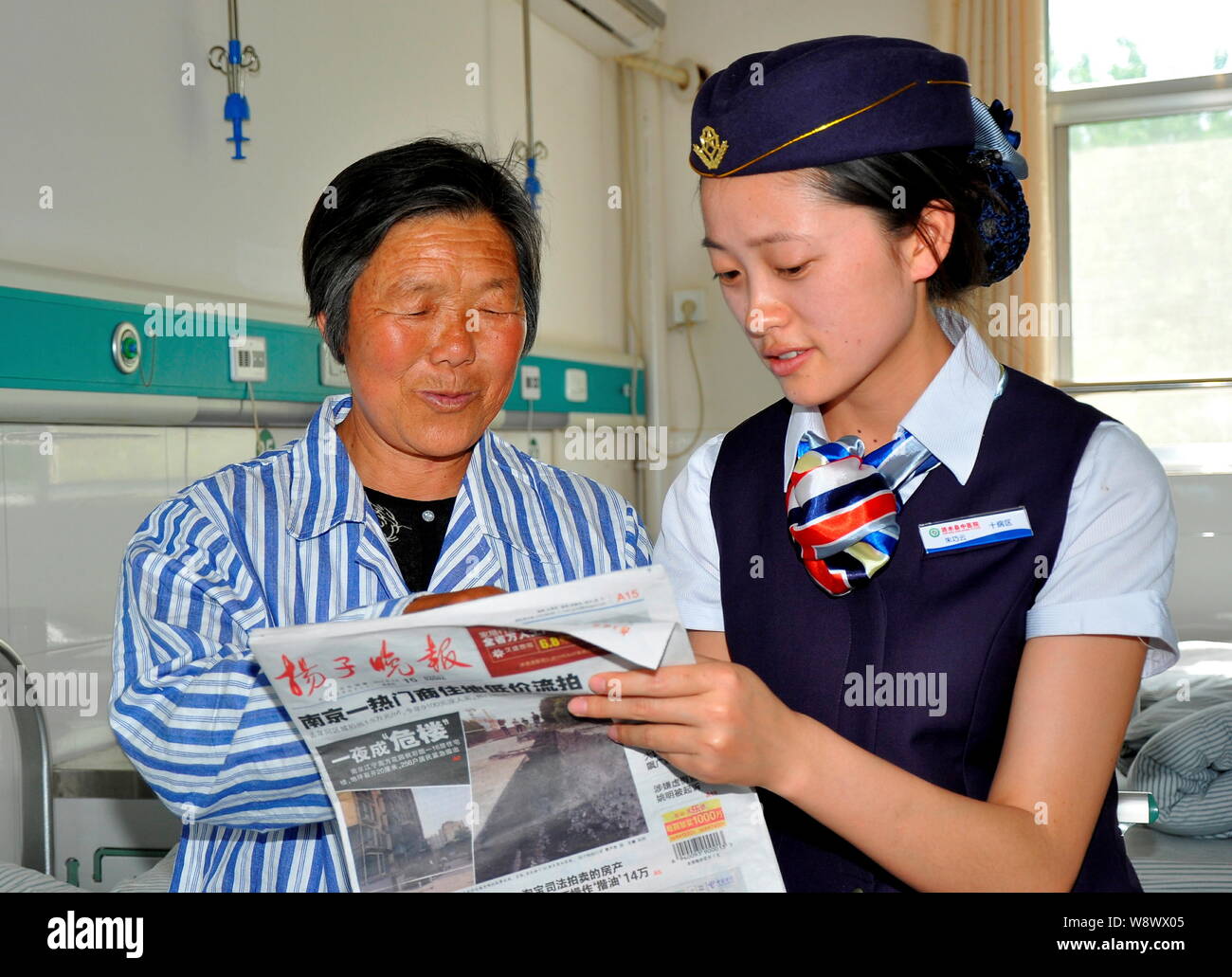 A Chinese nurse dressed like a flight attendant reads a newspaper with ...