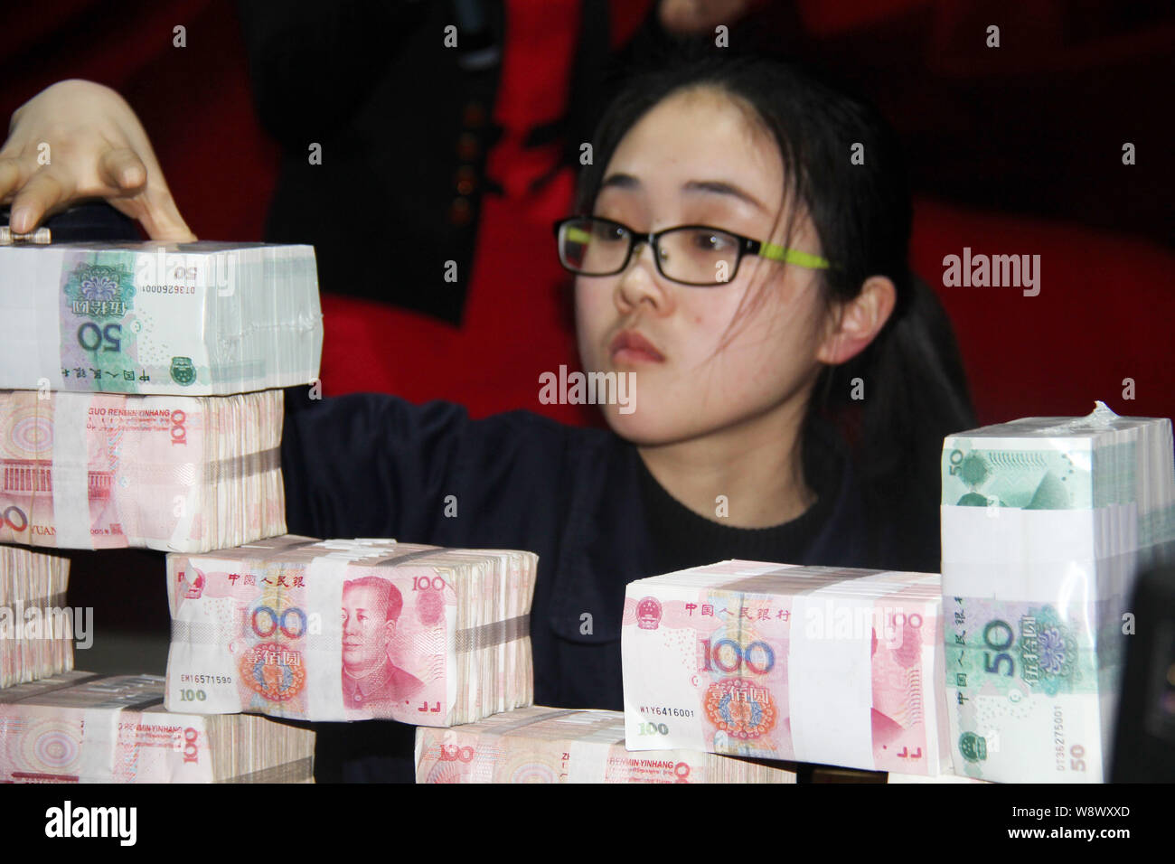 A Chinese employee stacks up bundles of RMB (renminbi) yuan banknotes ...