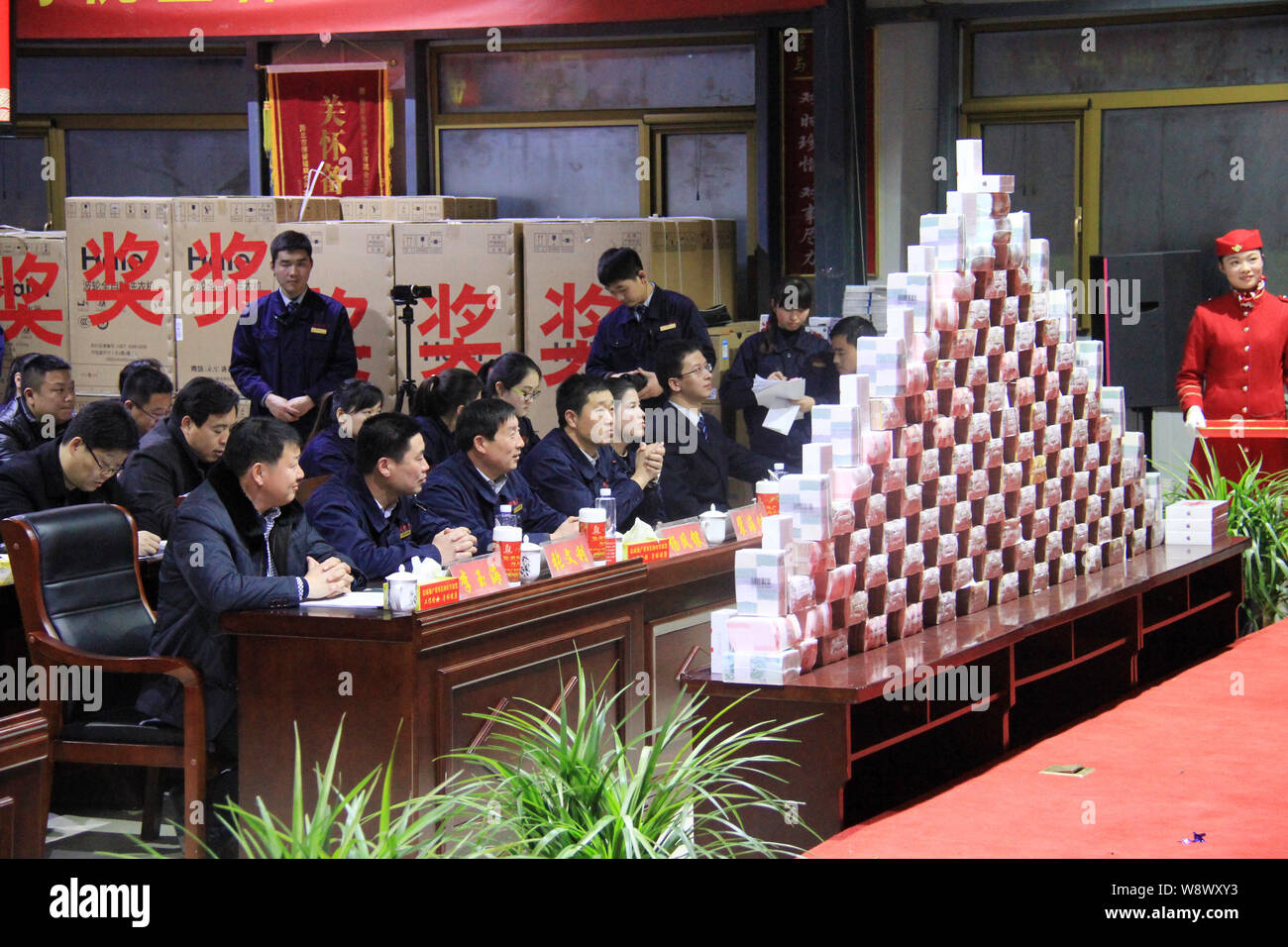Chinese employees look at a pyramid-shaped stack of RMB (renminbi) yuan ...