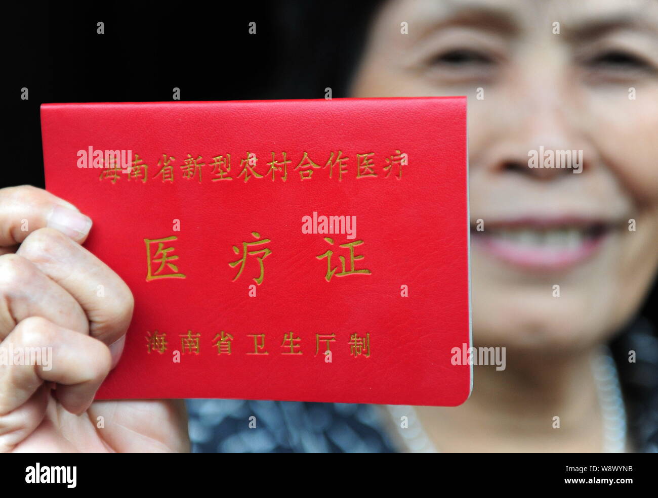 A local Chinese resident shows her health insurance card in Qionghai ...