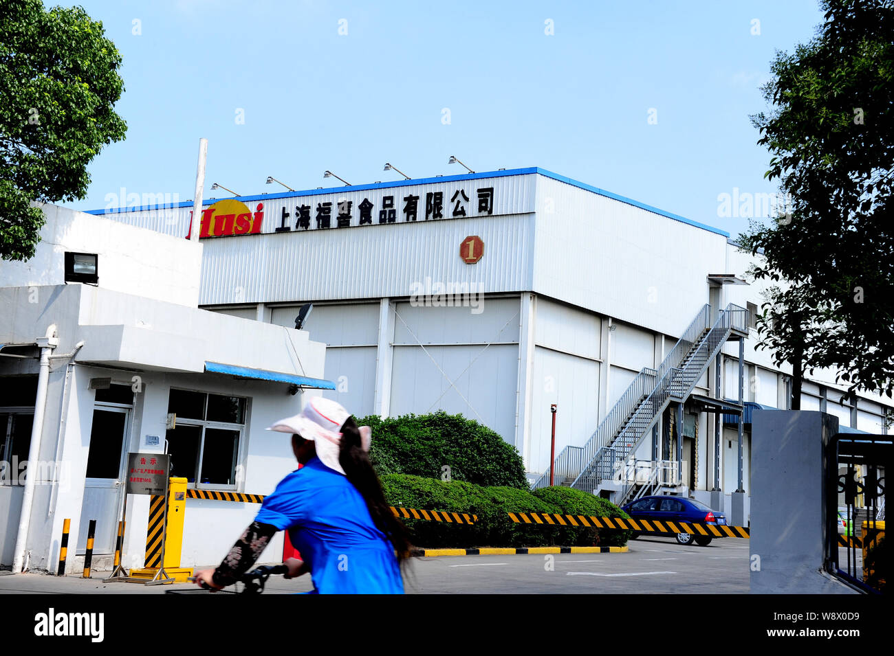A cyclist rides past the factory building of Shanghai Husi Food Co ...
