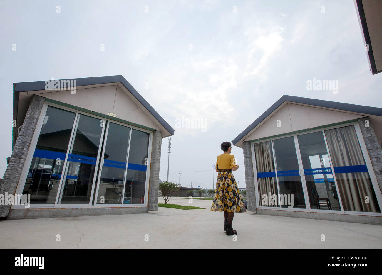 A woman walks past 3D printed houses at the Qingpu Park of the Shanghai ...