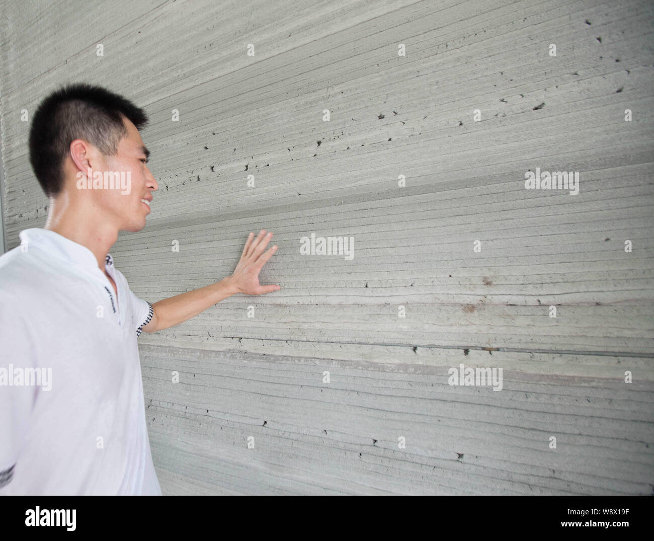 A man checks the wall of one of the ten 3D printed houses at the Qingpu ...