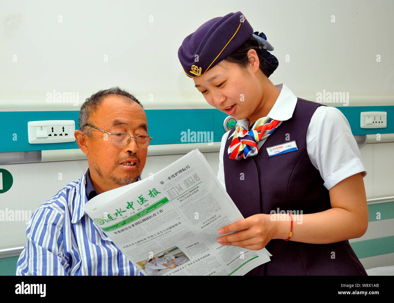 A Chinese nurse dressed like a flight attendant reads a newspaper with ...