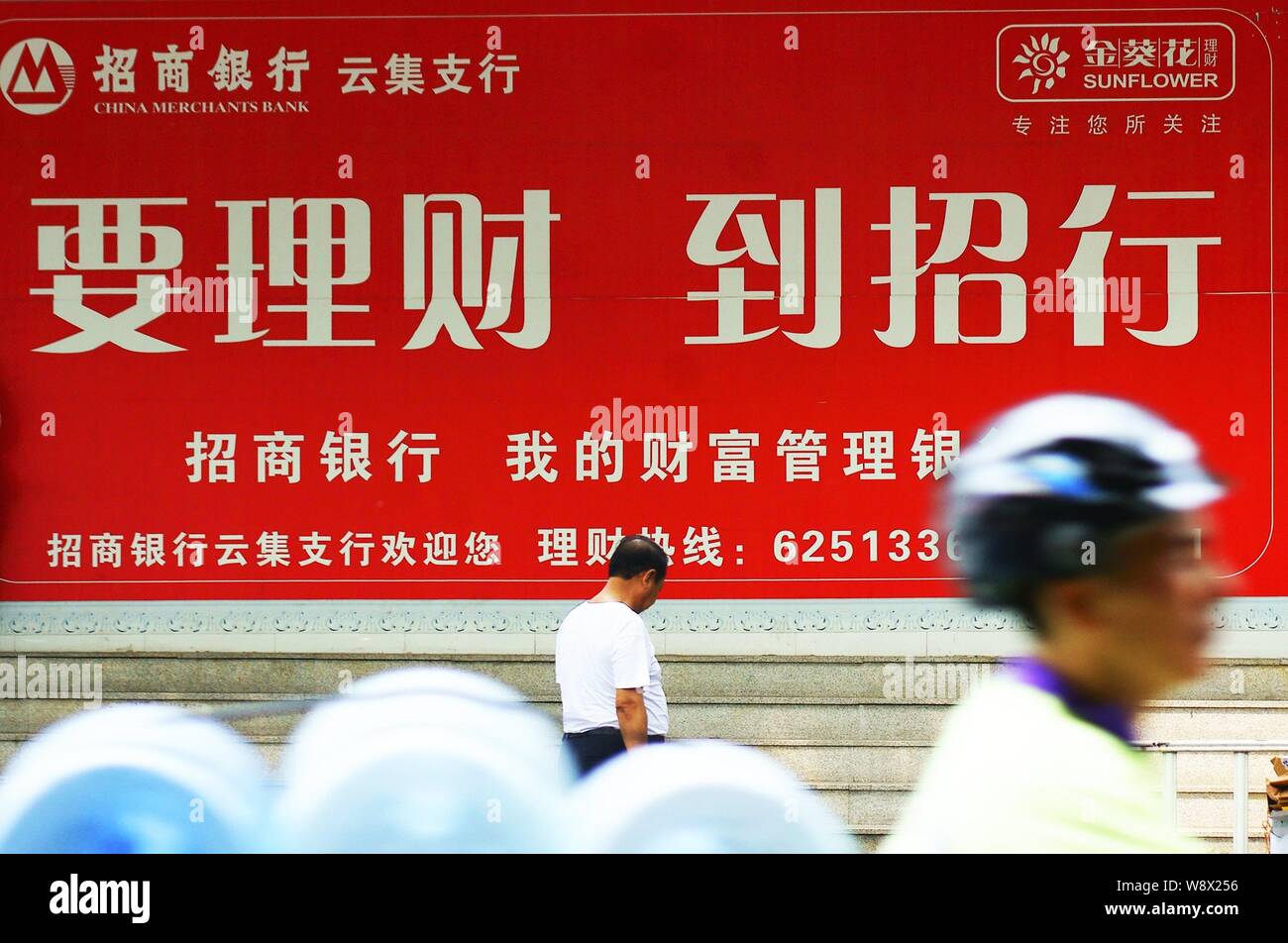 --FILE--A pedestrian walks past an advertisement for China Merchants ...