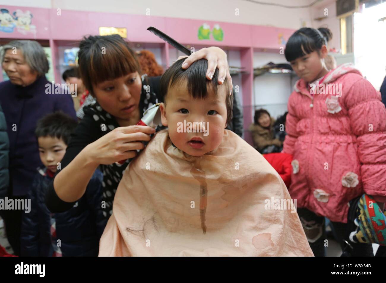 A Chinese kid has his hair cut at the barbers on Dragon Heads-raising ...