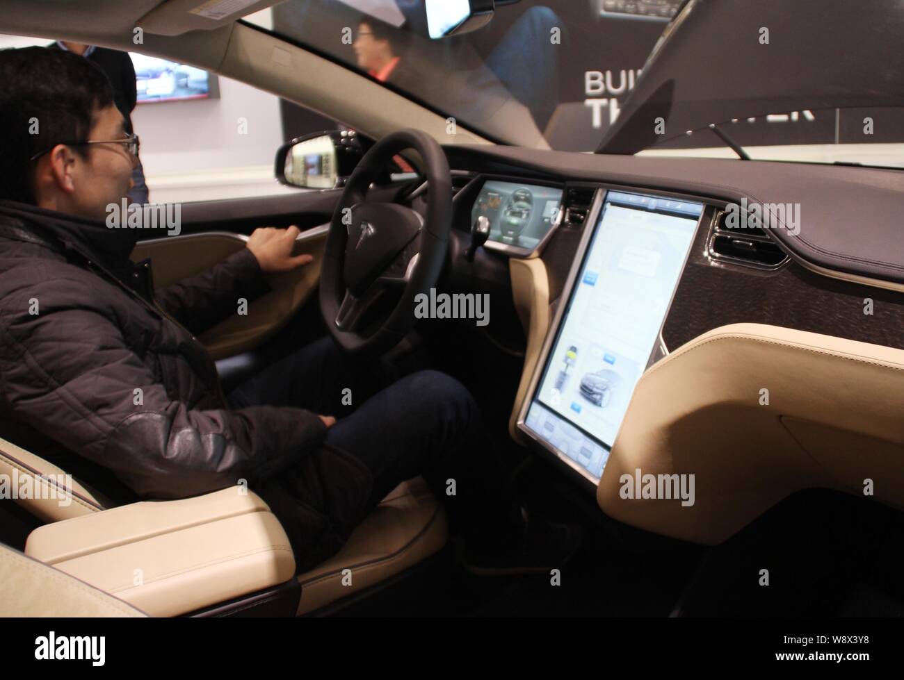 --FILE--A visitor tries out a Model S electric car on display at the ...