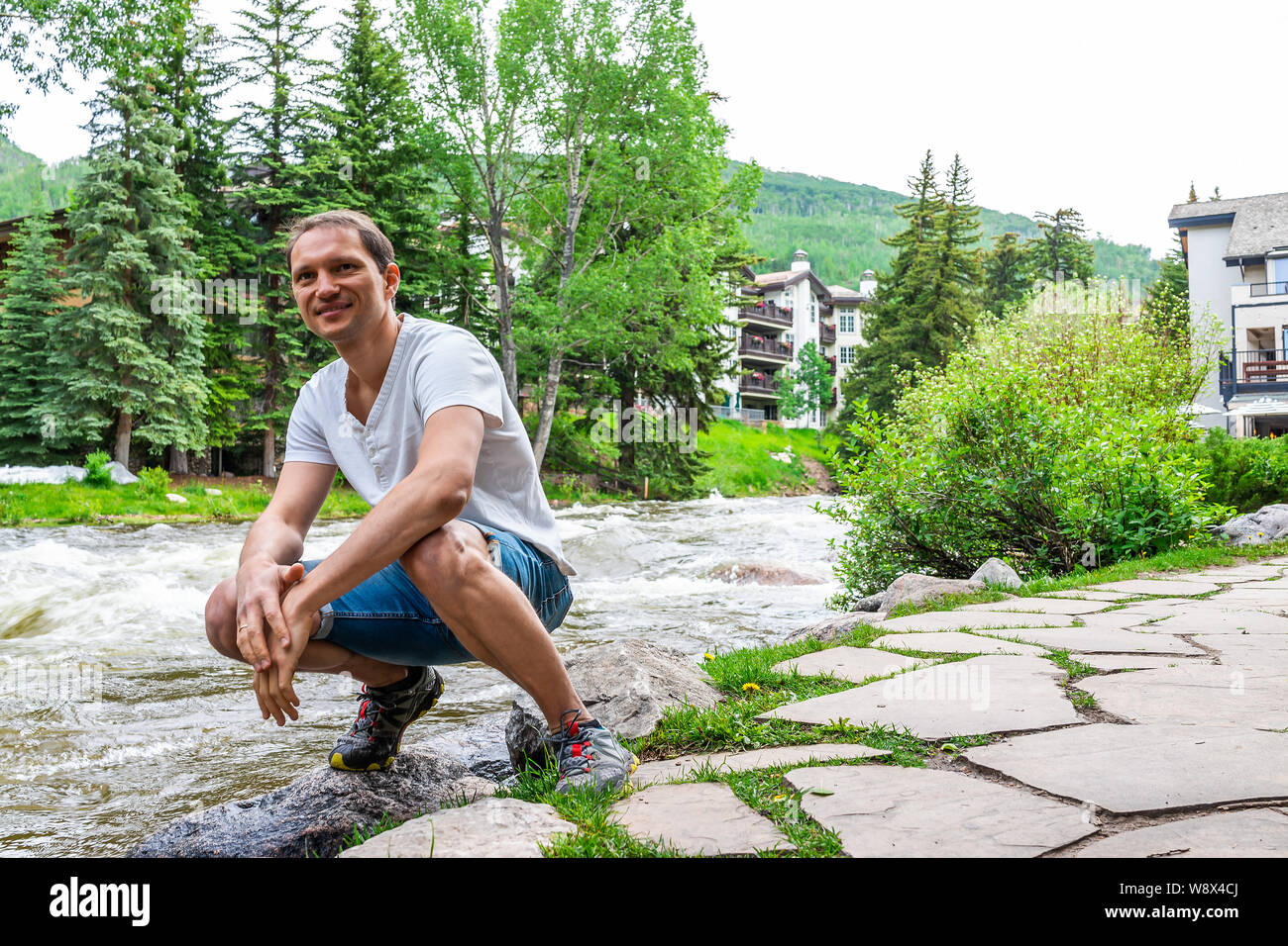 Man squatting sitting down in Vail, Colorado, USA European style resort ...