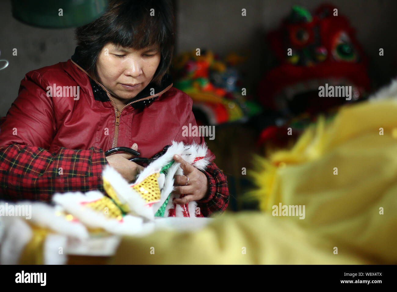 A female Chinese worker scissors cloaks to make dancing lions at a ...