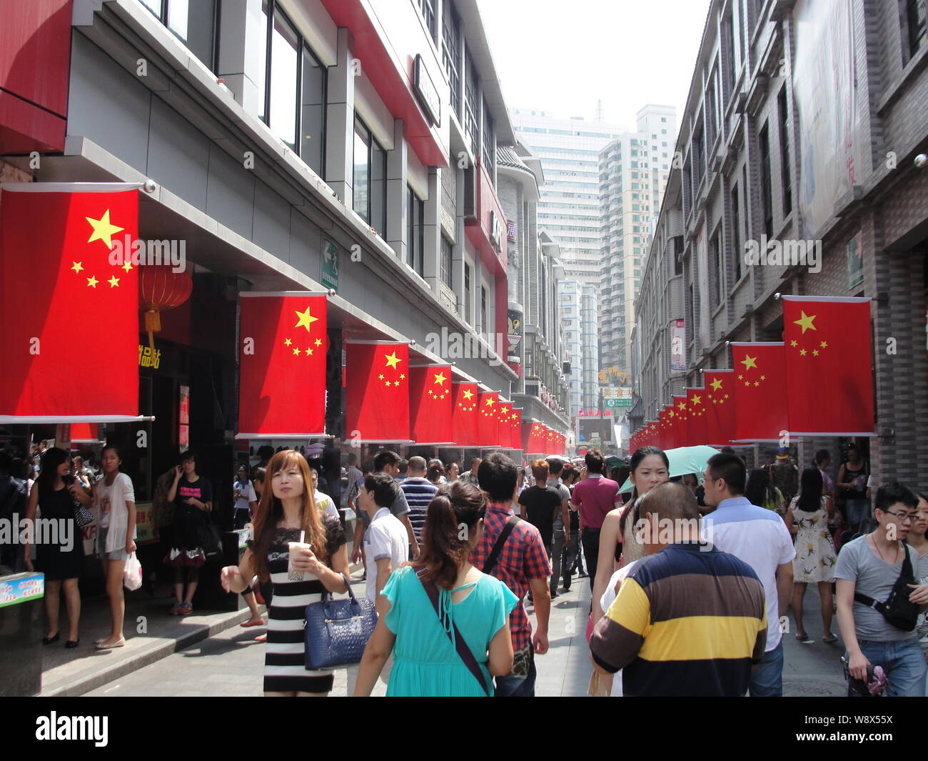 People walk past stores and shops decorated with Chinese national flags ...