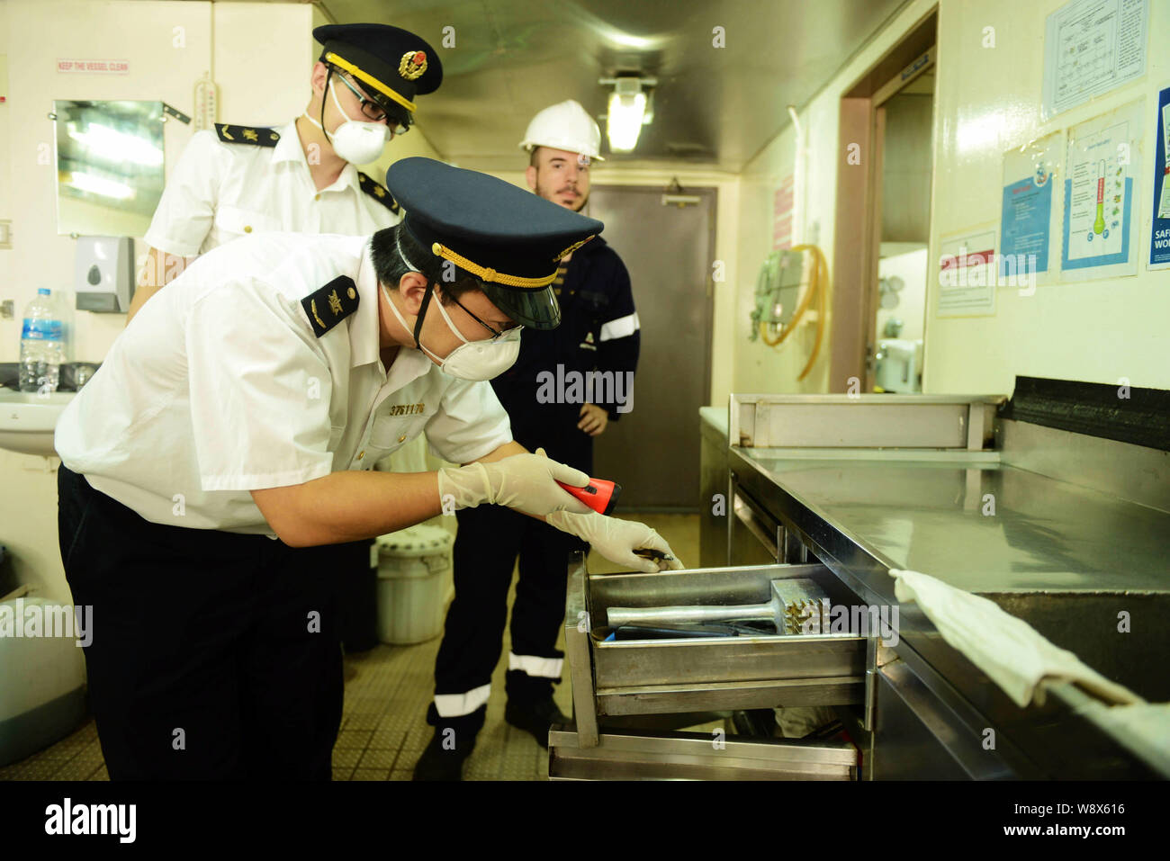 Chinese quarantine officers wearing masks examine a cabin in the bulk ...