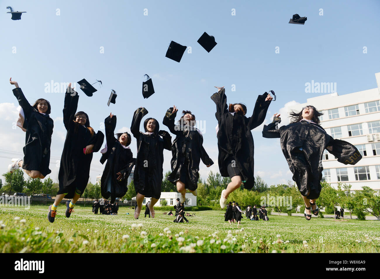--FILE--Chinese graduates dressed in academic gowns jump to throw hats ...