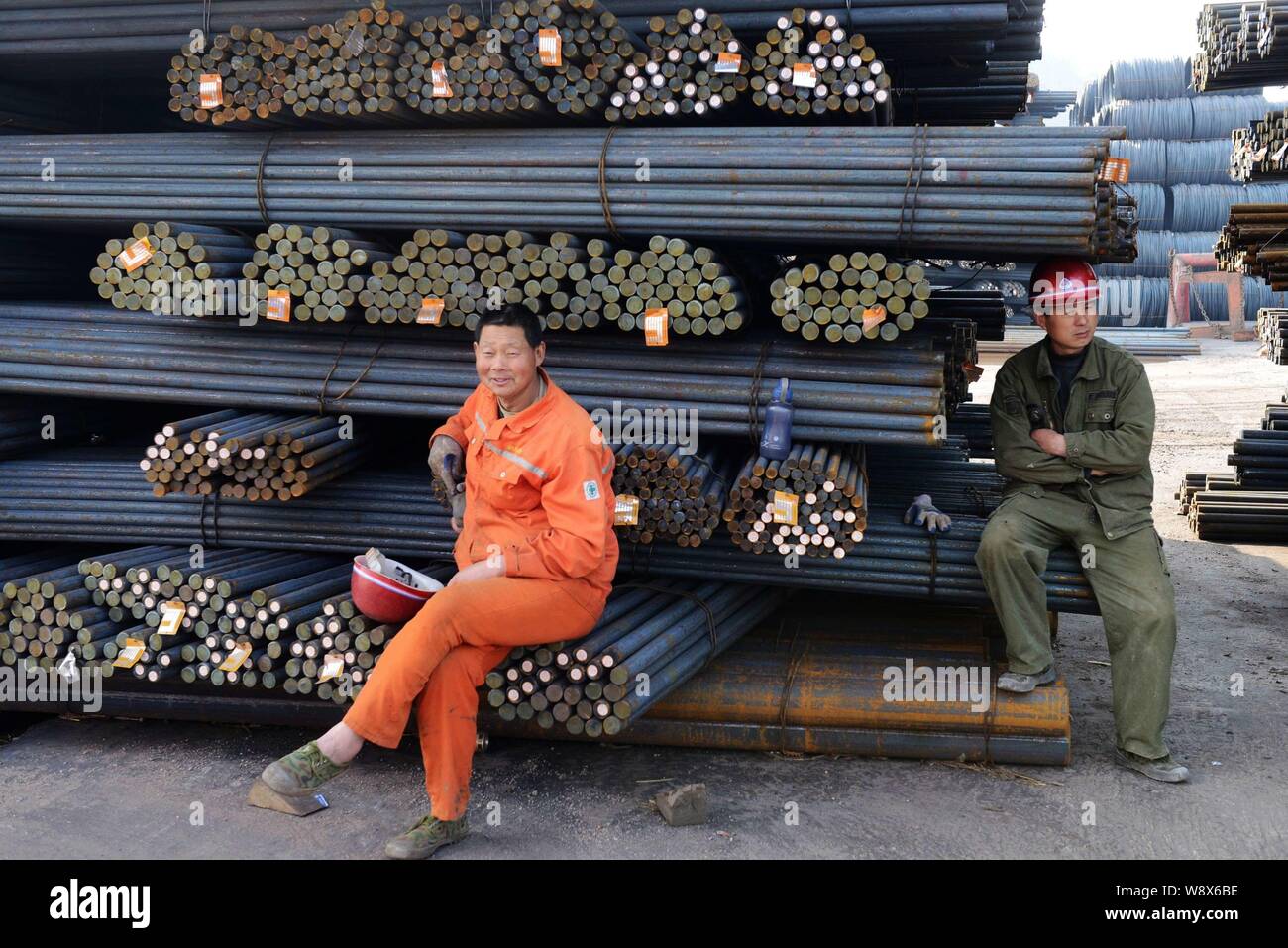 --FILE--Chinese workers rest on a stack of reinforcing steel rods on a ...