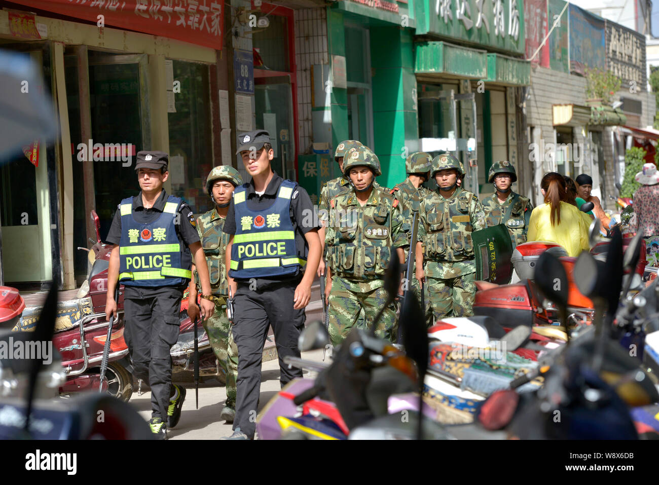 Chinese police officers and paramilitary policemen patrol a street in ...