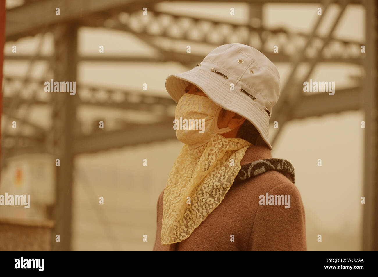 A woman wearing a face mask walks on a road in a sandstorm in Lanzhou ...