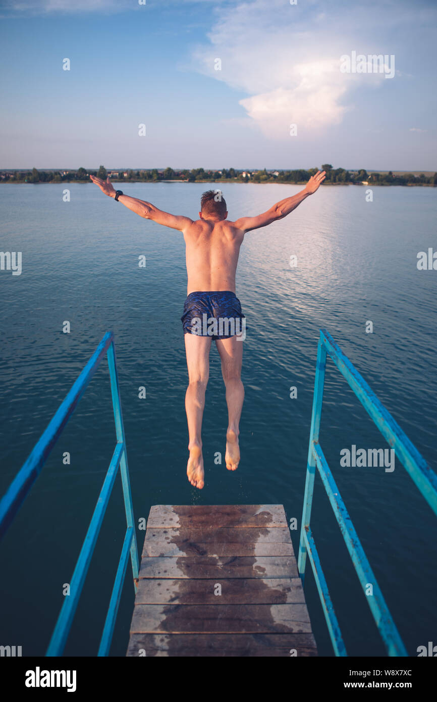man jumping from tower at lake water on sunset summer activities Stock ...