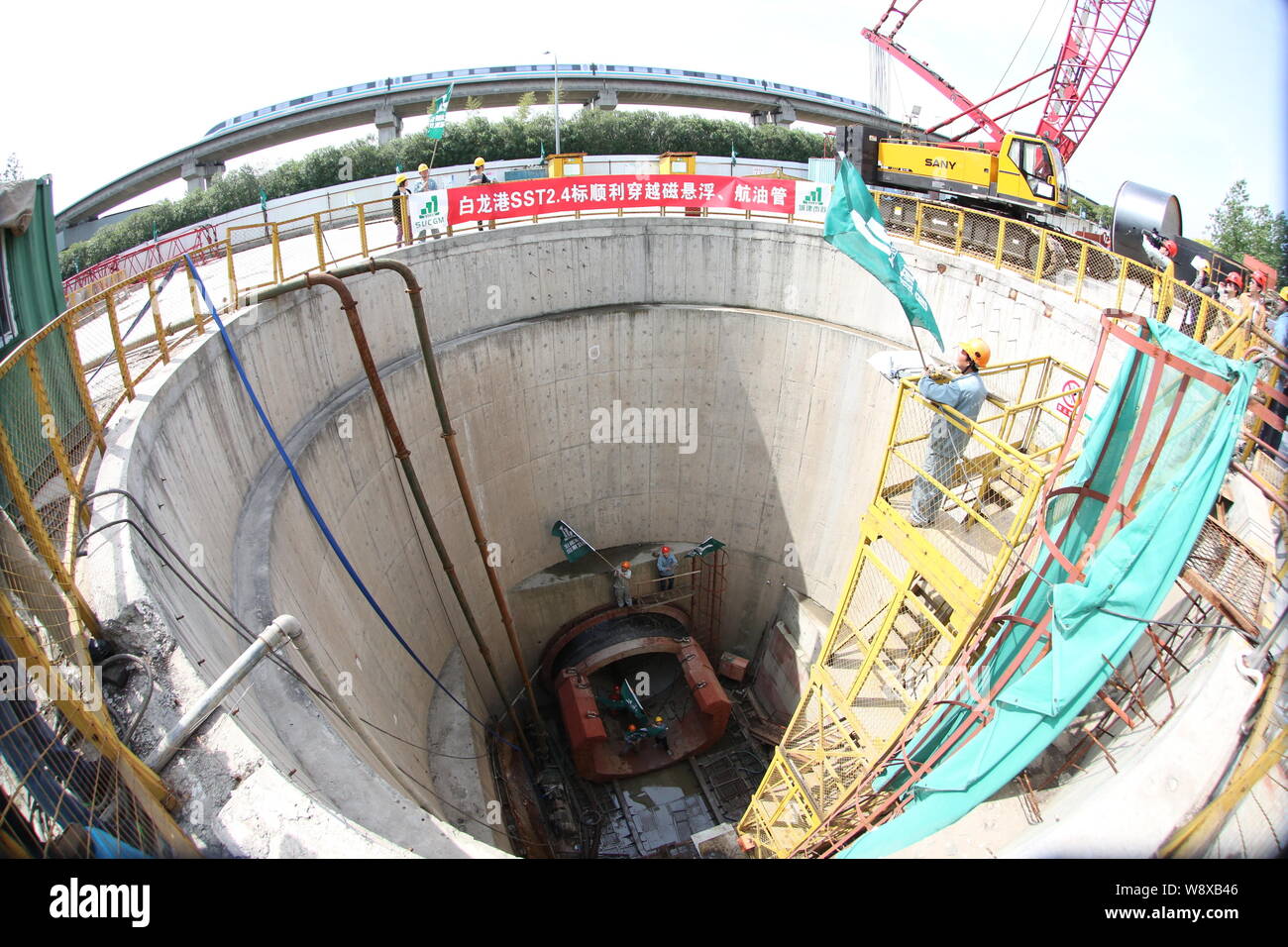 Workers wave flags as they succeed in laying a 4.64-meter sewage pipe ...