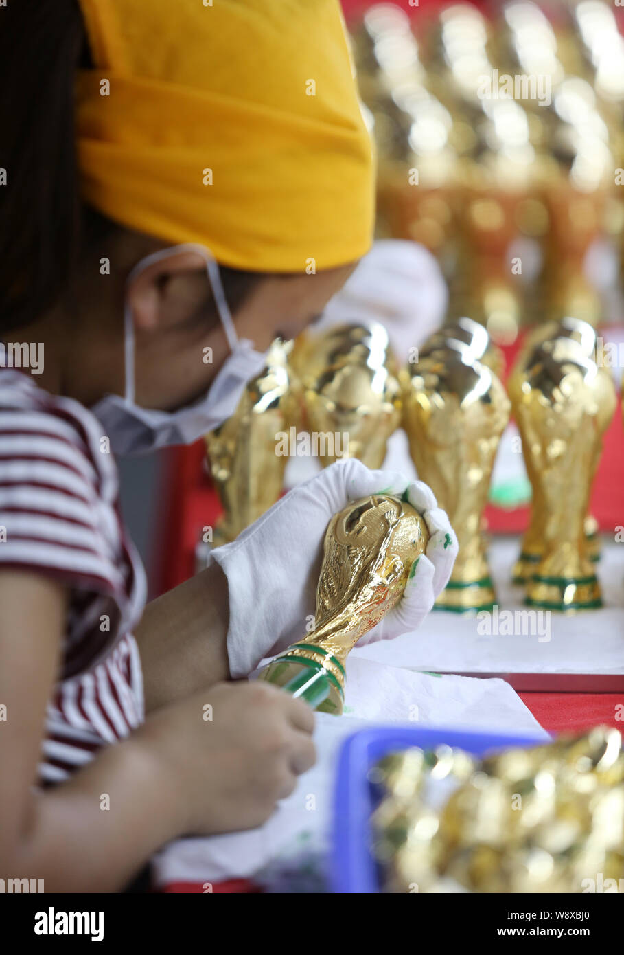 A female Chinese worker paints miniature FIFA World Cup trophies at the ...