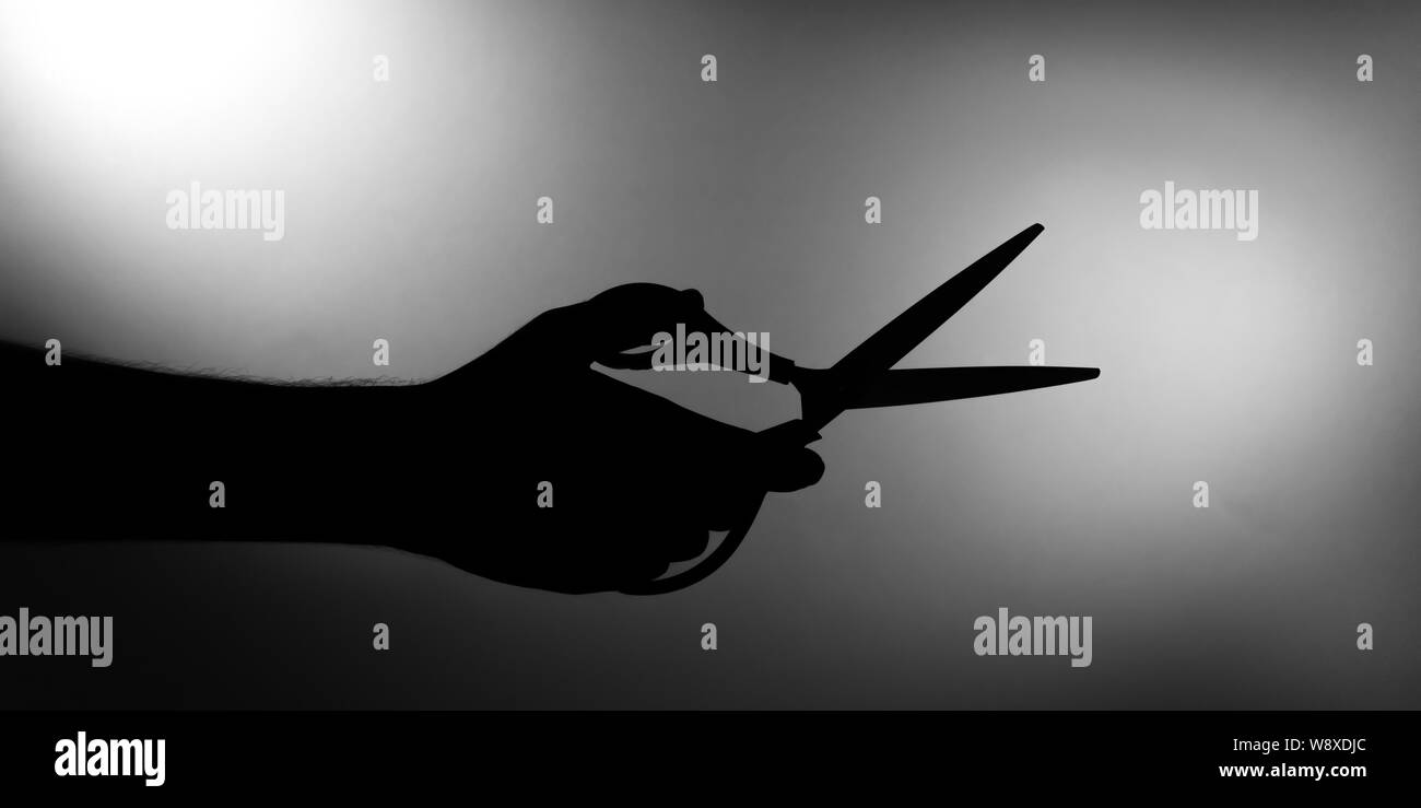 Man holds scissors in one hand silhouette Stock Photo - Alamy