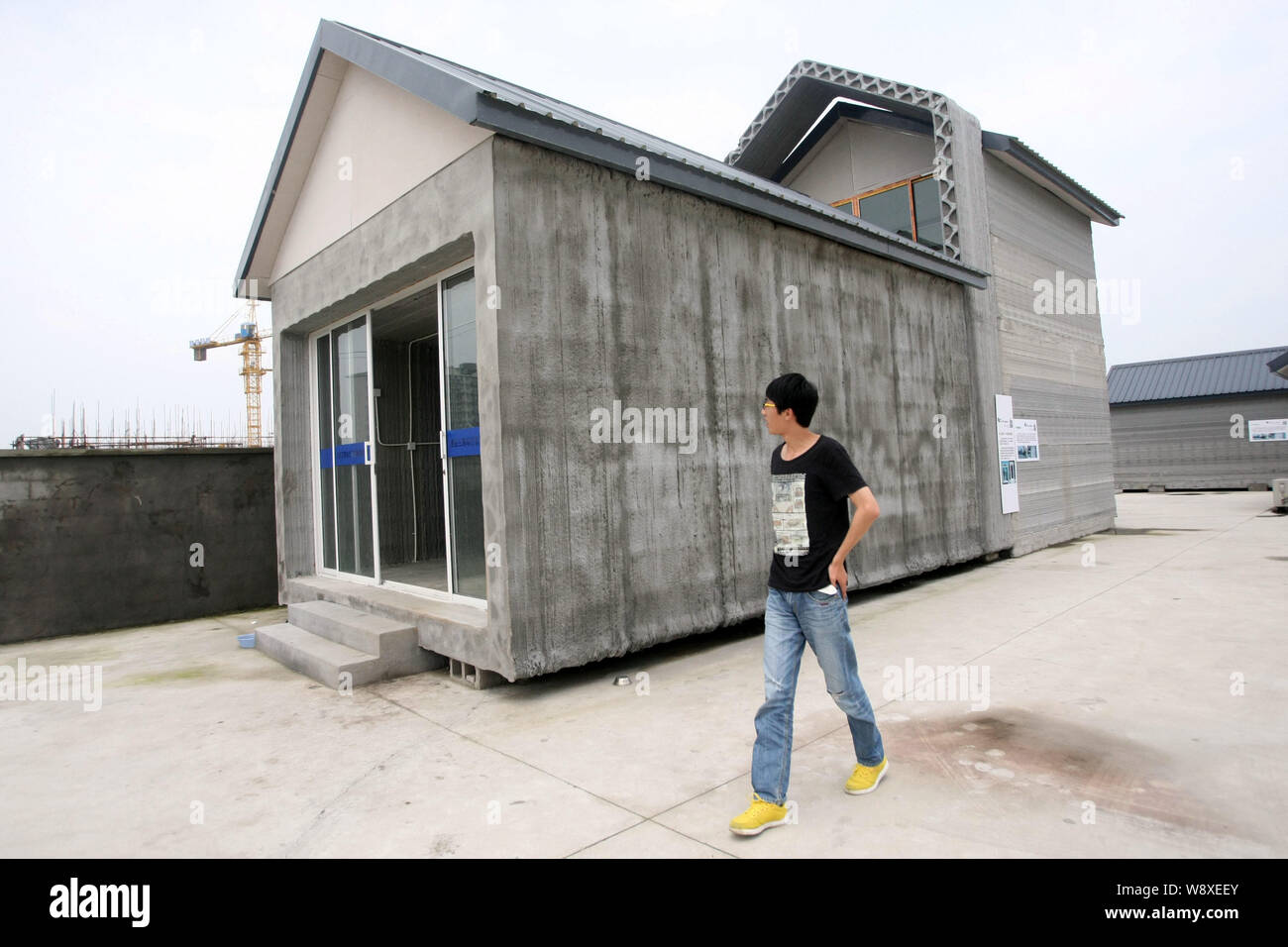 A man walks past one of the ten 3D printed houses at the Qingpu Park of ...